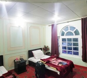 Quarto com cama, mesa de cabeceira, janela com cortinas e espelho na parede.