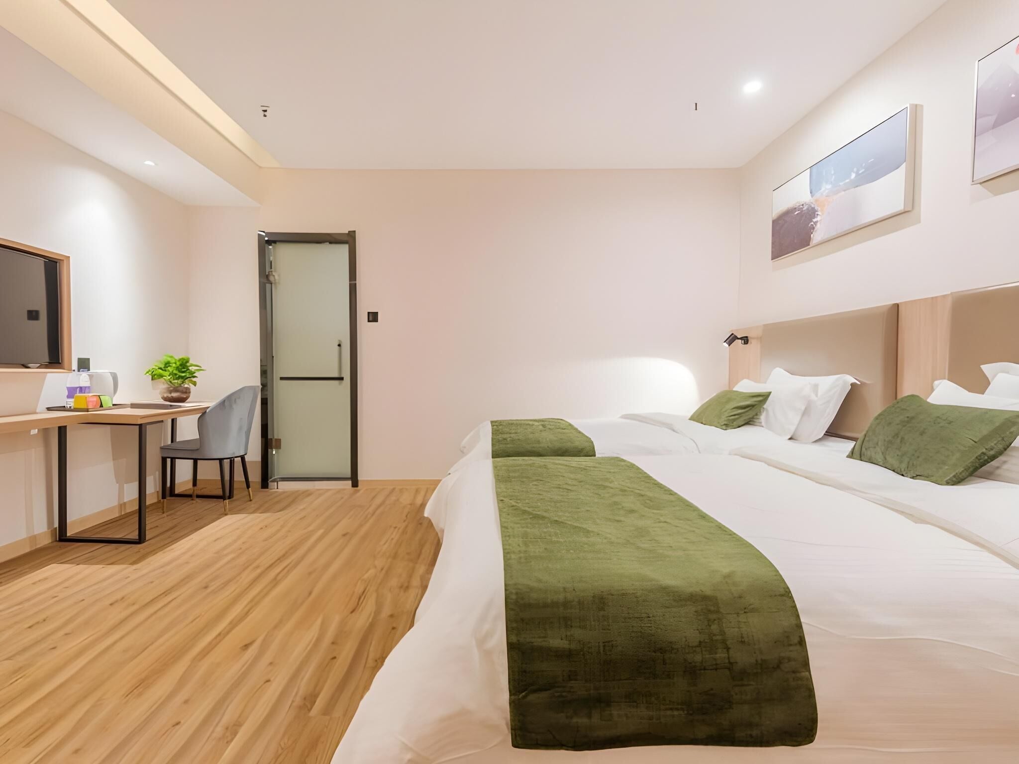 Quarto de hotel com cama, mesa de cabeceira, cadeira, escrivaninha e uma porta.