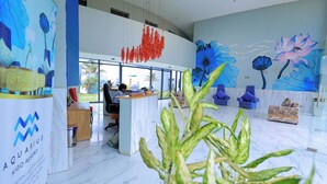 Um hall de hotel com balcão de recepção, área de estar e um mural de flores na parede.