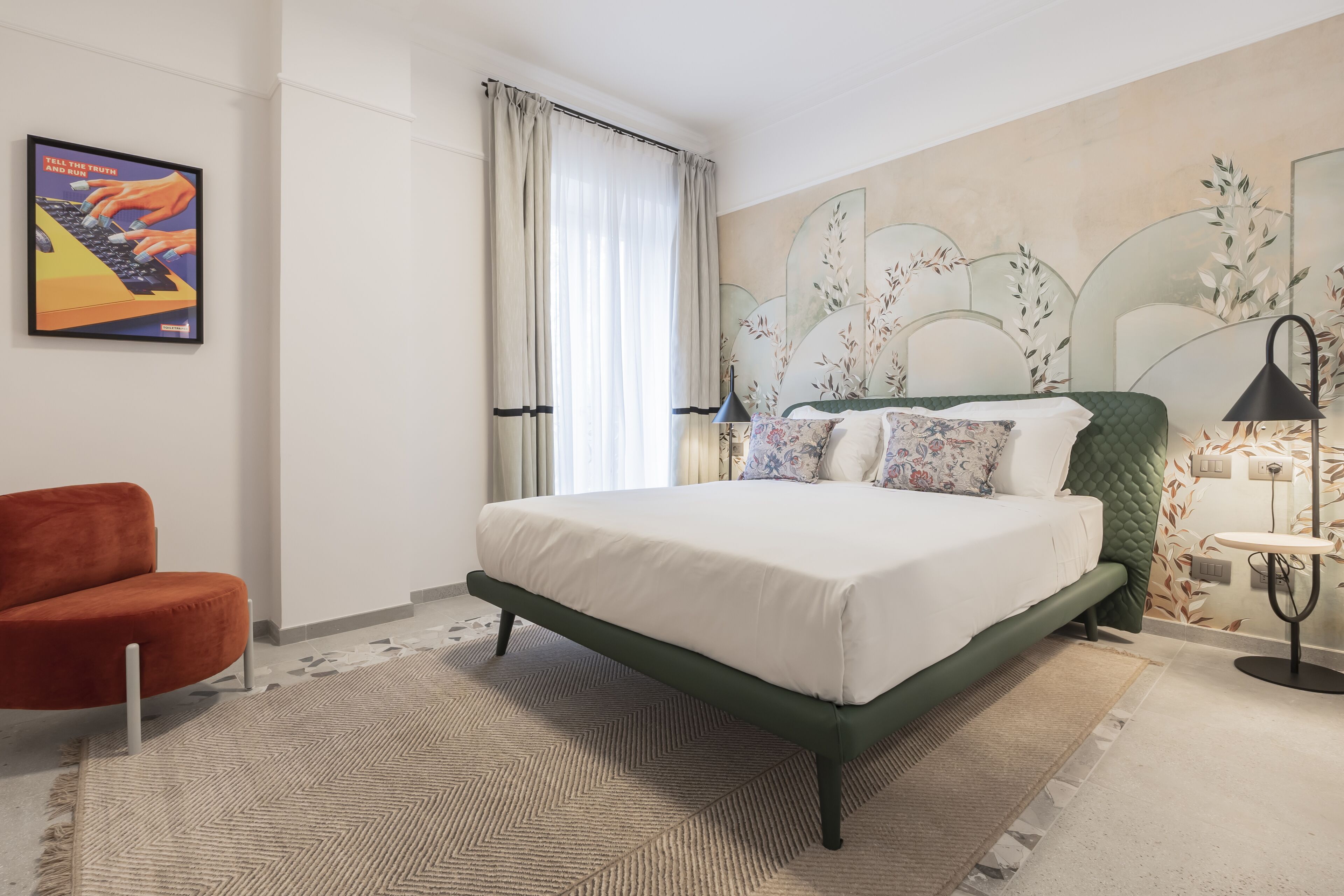Quarto com uma cama, uma cadeira, um abajur e uma obra de arte na parede.