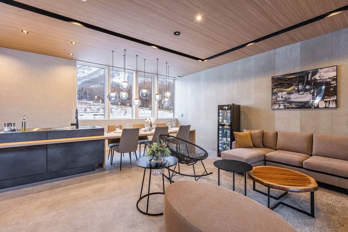 Uma sala de estar moderna com sofá, mesa de centro e área de jantar com cadeiras e mesa.