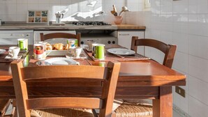 Cozinha moderna com azulejos brancos, fogão a gás e cadeiras de madeira em uma mesa de jantar.