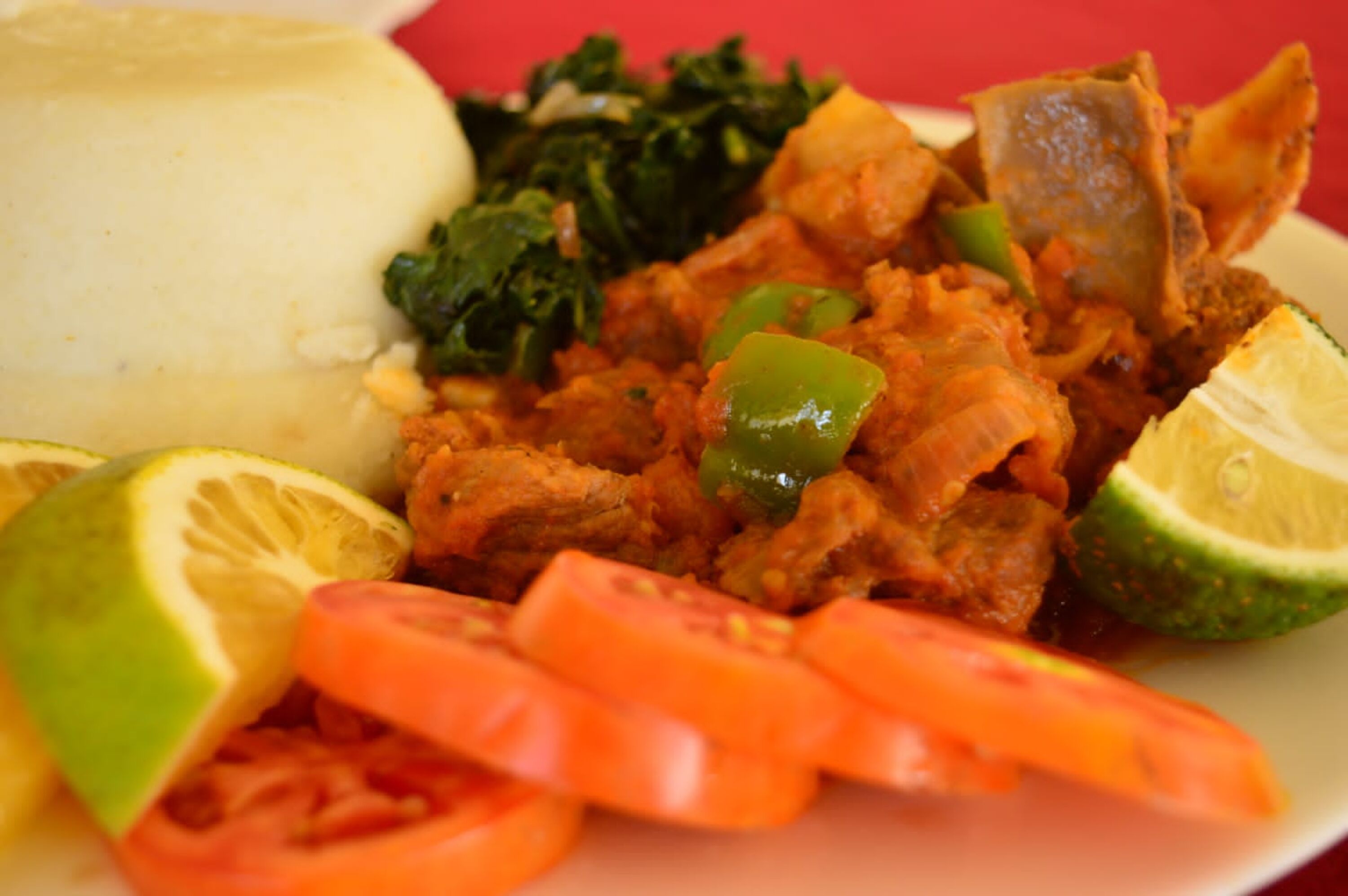 Um prato com diversos alimentos, incluindo um recipiente branco, possivelmente arroz, e um prato de carne com legumes.