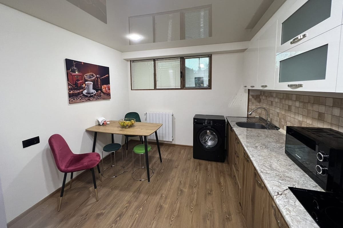 Uma cozinha compacta com máquina de lavar, pia e área de jantar com mesa e cadeiras.