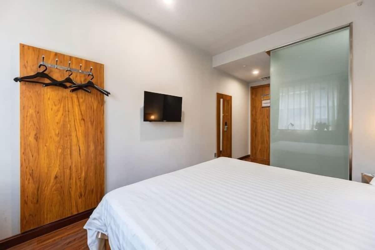 Quarto com cama, guarda-roupa de madeira, televisão e porta de correr.