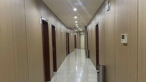 Um corredor comprido e estreito, com painéis de madeira nas paredes e chão de azulejos.
