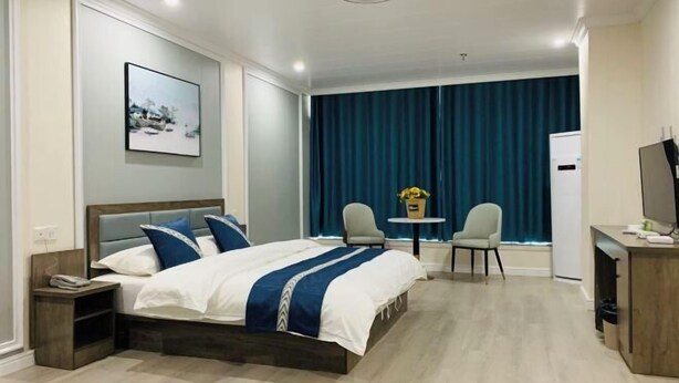 Quarto de hotel com cama, mesa de cabeceira, televisão e escrivaninha com cadeira.