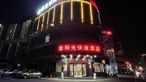 Um hotel com um letreiro iluminado em destaque e um estacionamento à frente.