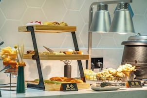 Buffet com diversas opções de comida, um espaço para café e uma panela de sopa.