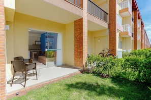 Um edifício com telhado plano, varanda e porta que dá para um quarto com janela.