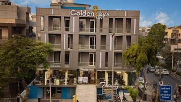 Um edifício de vários andares com uma placa indicando 'Goldenkeys Inn' e um salão chamado 'Friendly Salon' no andar térreo.