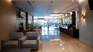 Um lobby moderno com balcão de recepção, área de estar e grandes janelas.