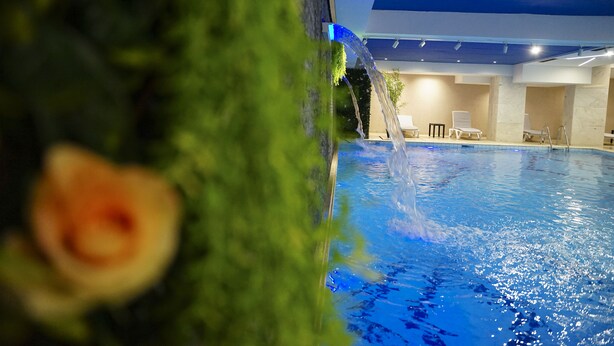 Piscina com um elemento aquático, espreguiçadeiras e design arquitetônico moderno.