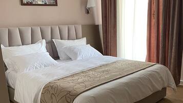 Uma cama bem arrumada, com cabeceira, luminária de cabeceira e um quadro na parede.