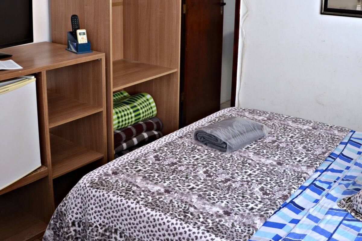 Quarto com cama, guarda-roupa, escrivaninha e cadeira.