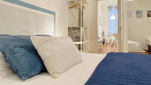 Quarto com cama, almofadas, guarda-roupa e escrivaninha.