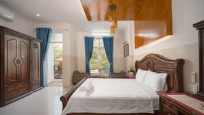 Quarto de hotel com uma cama grande, móveis de madeira, uma escrivaninha e vista para o exterior.
