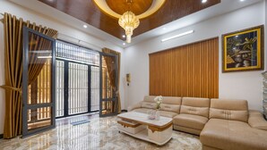 Uma sala de estar espaçosa com um sofá bege, uma mesa de centro e um lustre.
