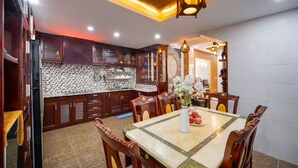 Uma cozinha moderna com armários de madeira escura, painel de azulejos e uma área de refeições com mesa de mármore e cadeiras de madeira.