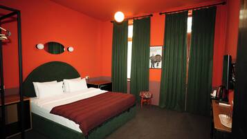 Quarto com cama, mesa de cabeceira, cadeira, escrivaninha, espelho e janela com cortinas.