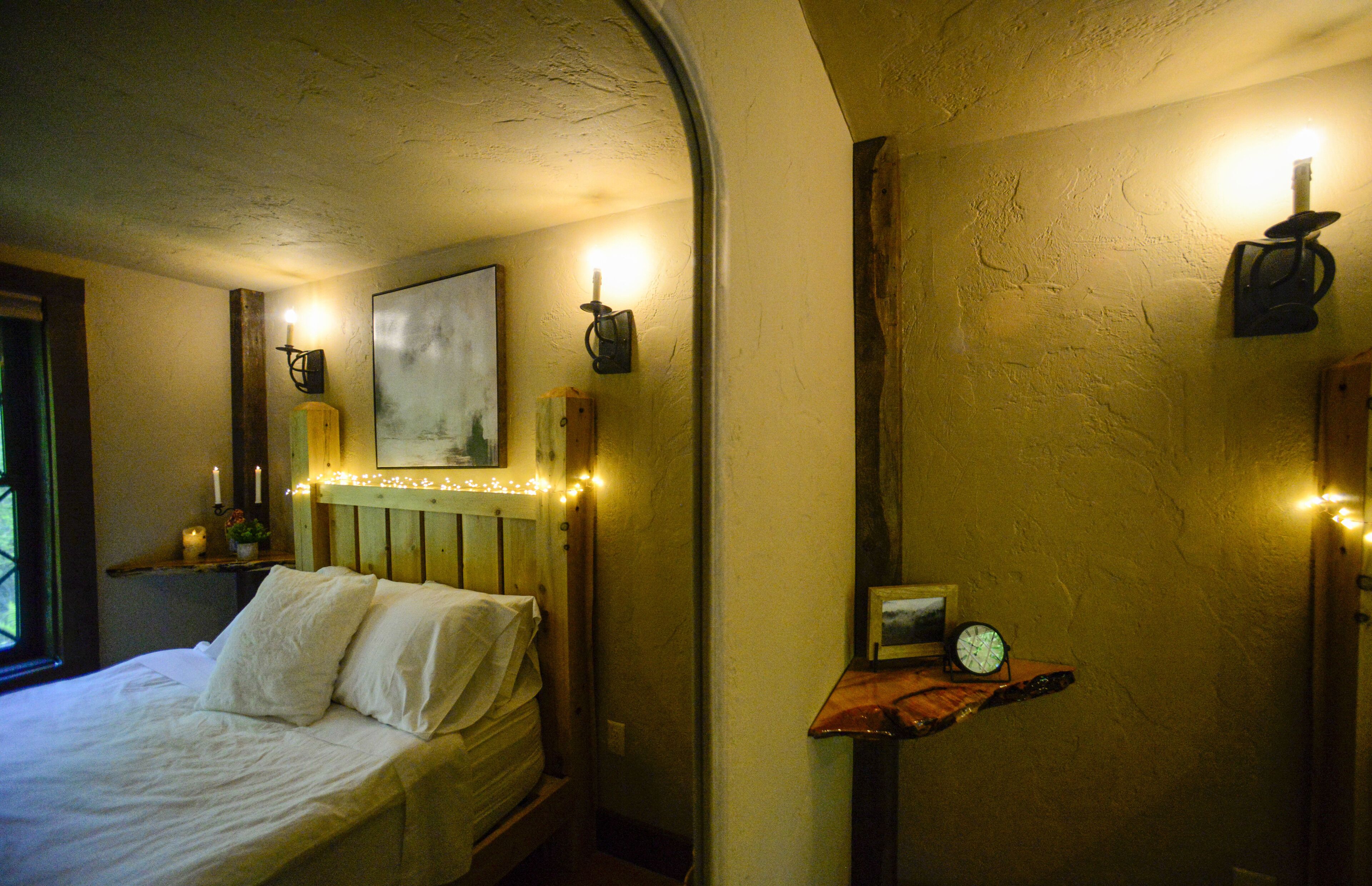 Quarto com cama, luminárias na parede, relógio e quadro emoldurado.