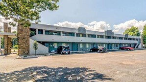 Um motel moderno com uma fileira de quartos, estacionamento e fachada de pedra.
