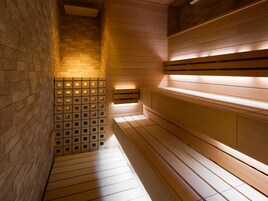 Uma sauna com bancos de madeira e parede de tijolos.