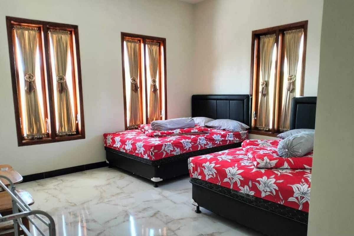 Quarto de hotel com duas camas, uma escrivaninha e uma cadeira.