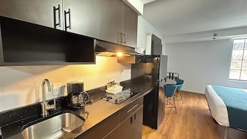 Um frigorífico/congelador grande, um micro-ondas, uma cafeteira/bule