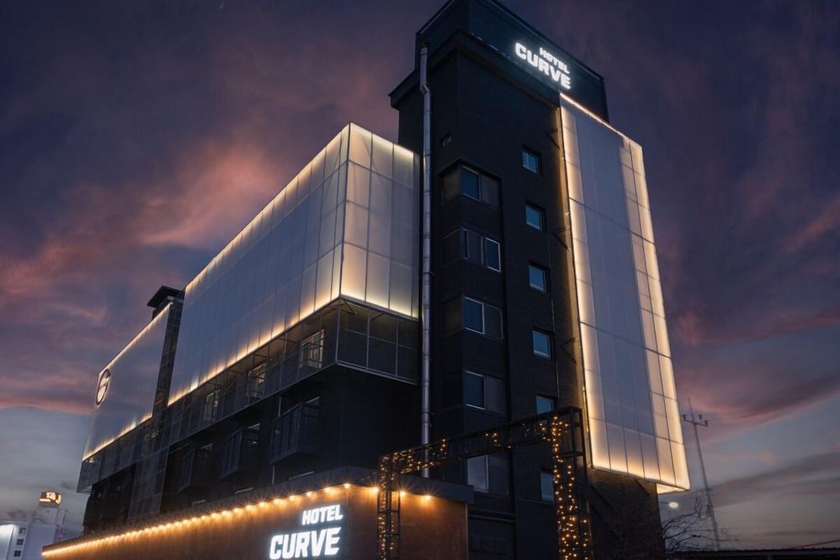 Um edifício de hotel moderno com uma placa de destaque que diz 'HOTEL CURVE'.