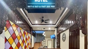 Uma área de recepção de hotel com uma parede de azulejos coloridos, um balcão de recep ção, uma televisão e um relógio na parede.