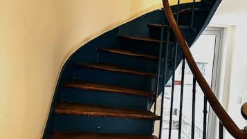 Uma escadaria em espiral com degraus de madeira e corrimãos de metal preto.