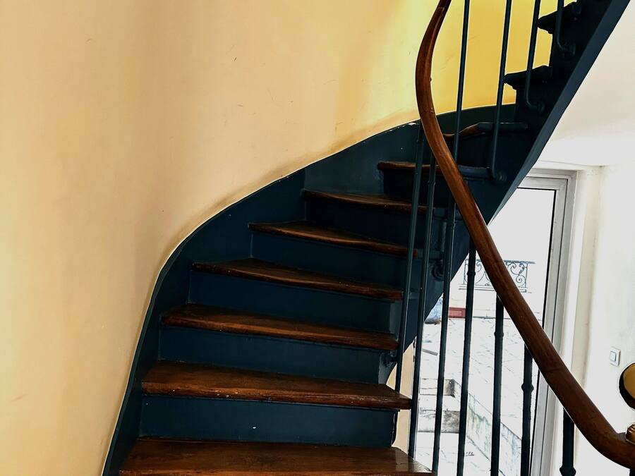Uma escadaria em espiral com degraus de madeira e corrimãos de metal preto.