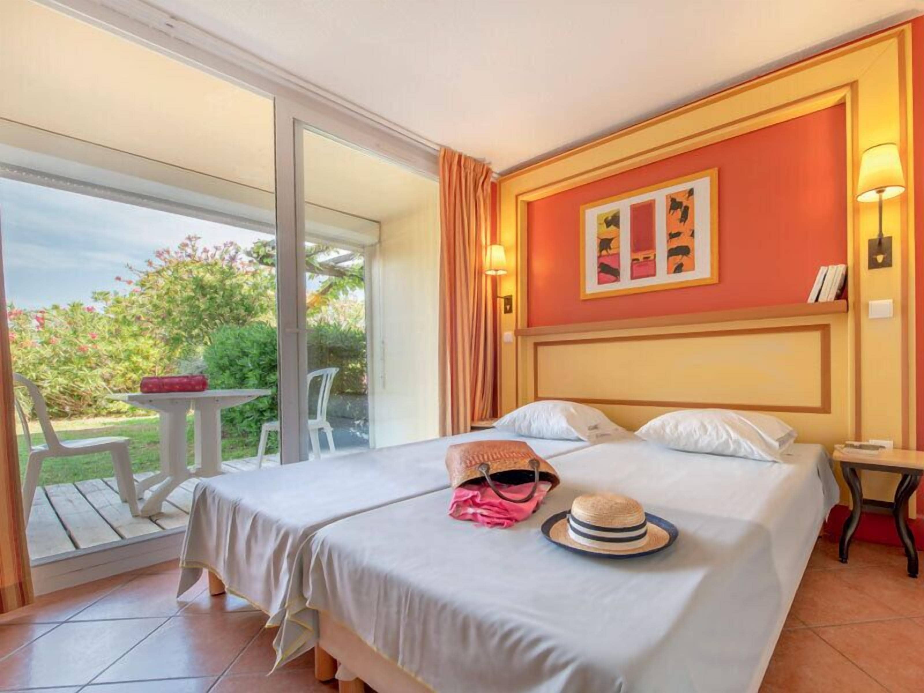 Quarto de hotel com cama, mesa e uma cadeira em frente à janela.