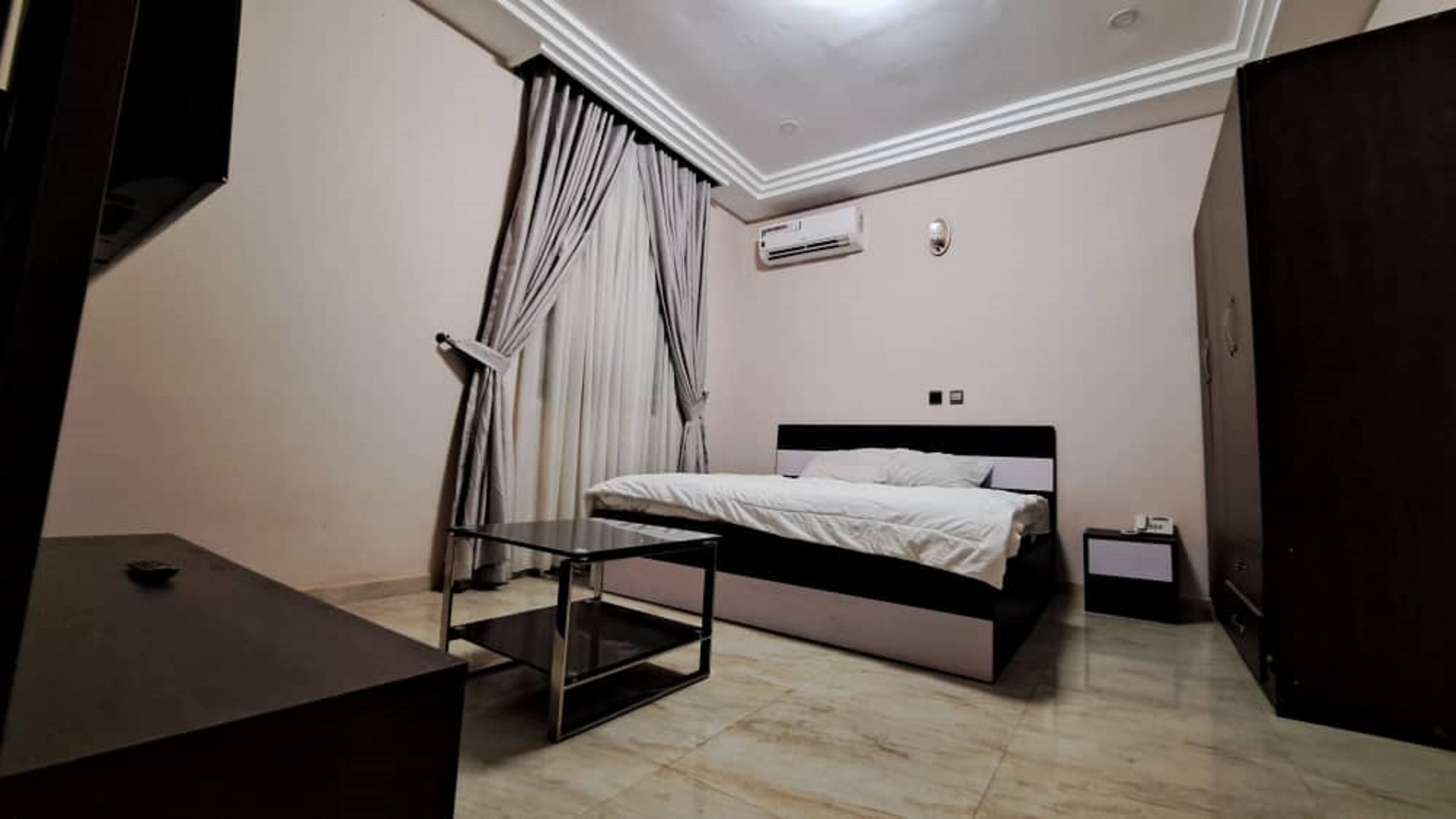 Quarto com cama, escrivaninha, cadeira, ar condicionado e armário.