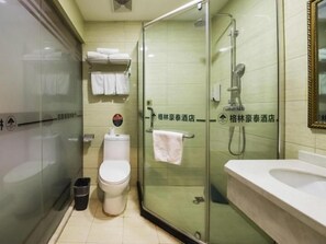 Uma casa de banho moderna com cabine de chuveiro em vidro, sanita e lavatório.