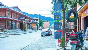 Ruas com edifícios tradicionais, uma árvore com balanço de pneu e motocicletas estacionadas.