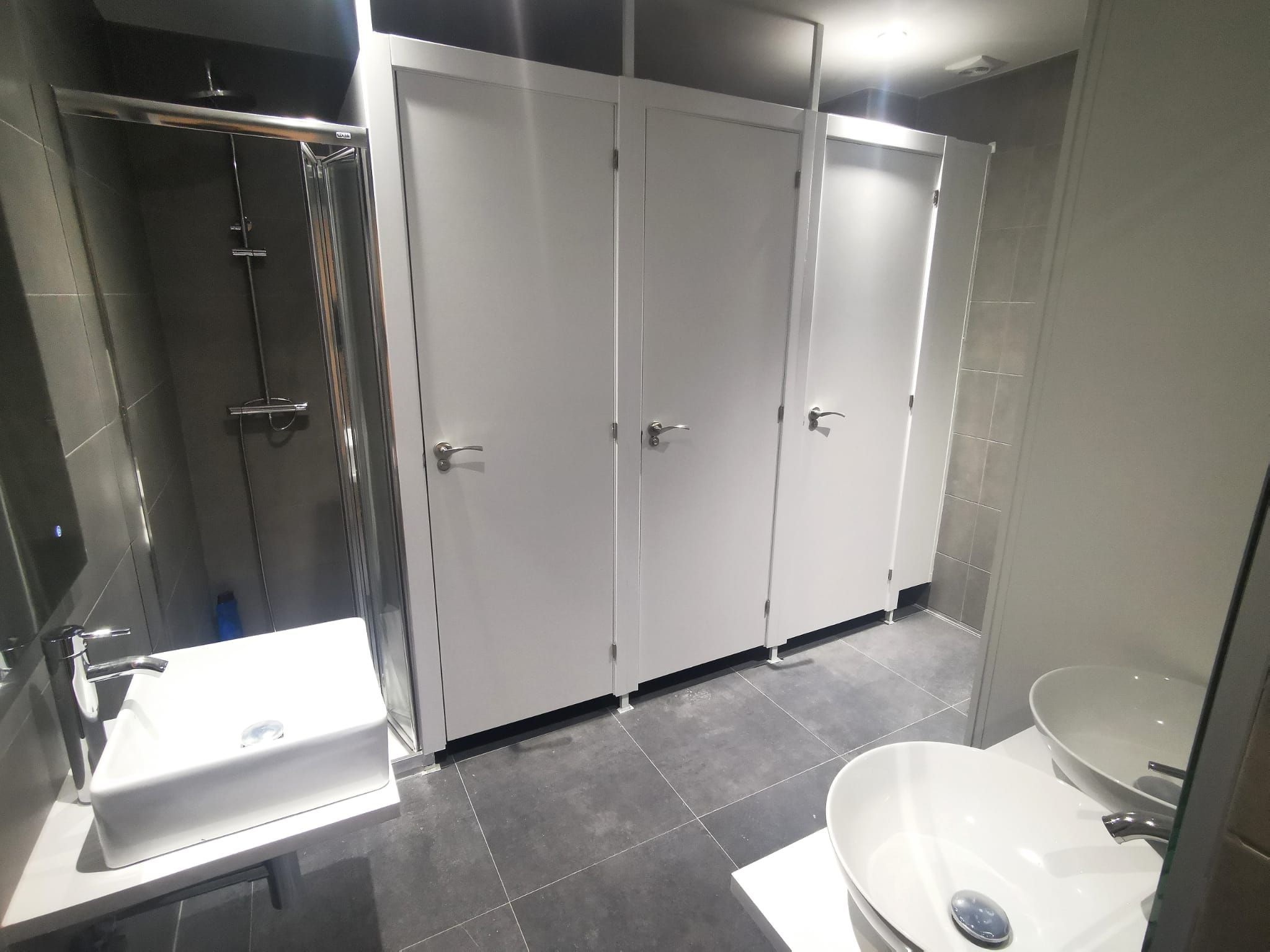 Uma casa de banho moderna com um espelho grande, uma pia, uma banheira e um chuveiro.