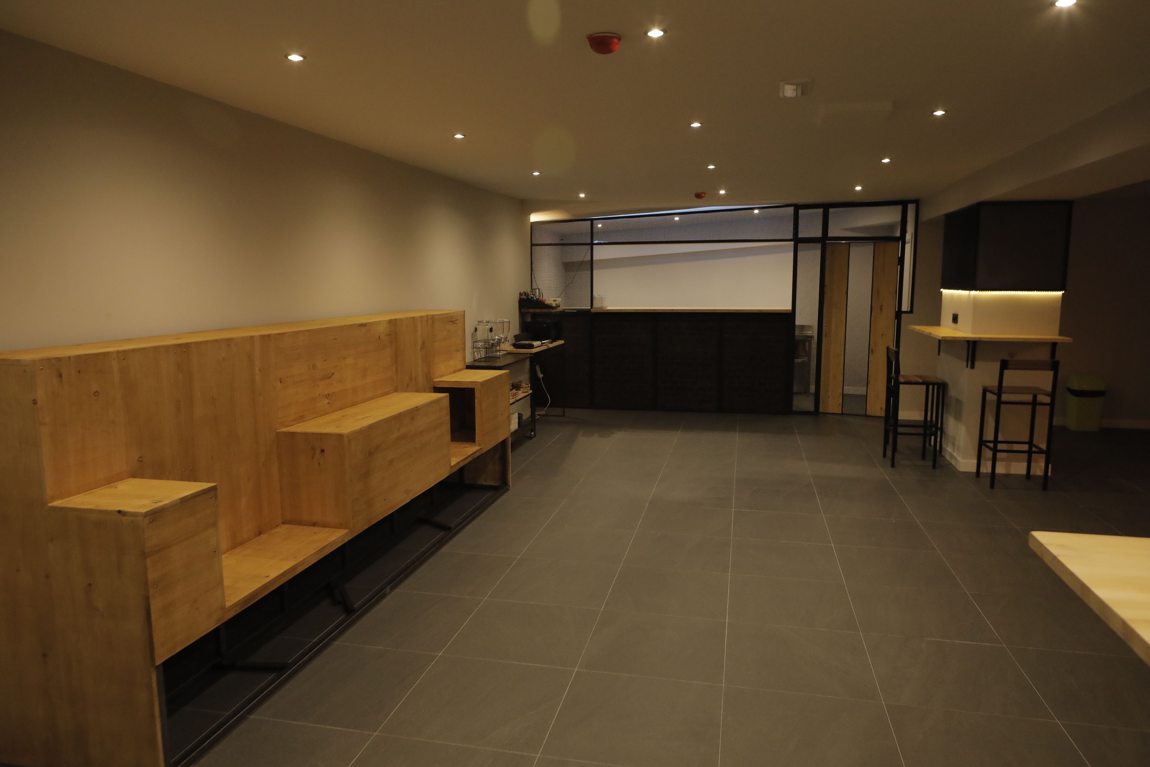 Um interior moderno com área de estar com banco de madeira, bancada de cozinha e espaço para bar.