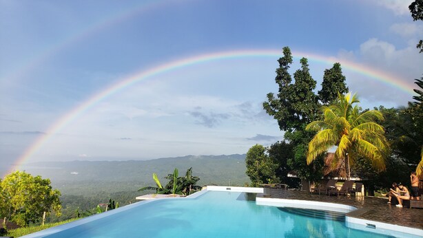 Piscina com vista para montanhas e um arco-íris.