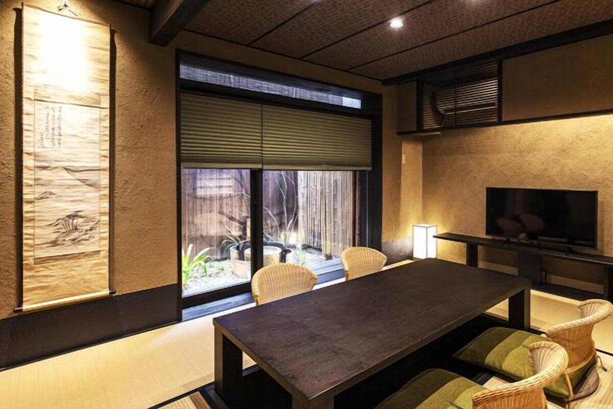 Um quarto em estilo japonês tradicional, com tatame, uma mesa baixa e uma televisão.