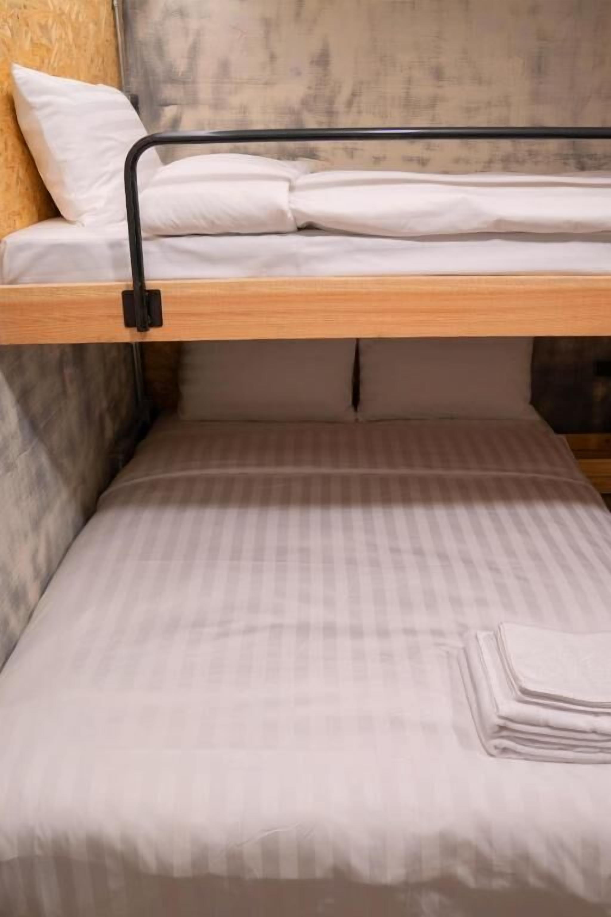 Uma cama beliche com estrutura de madeira e roupa de cama branca.
