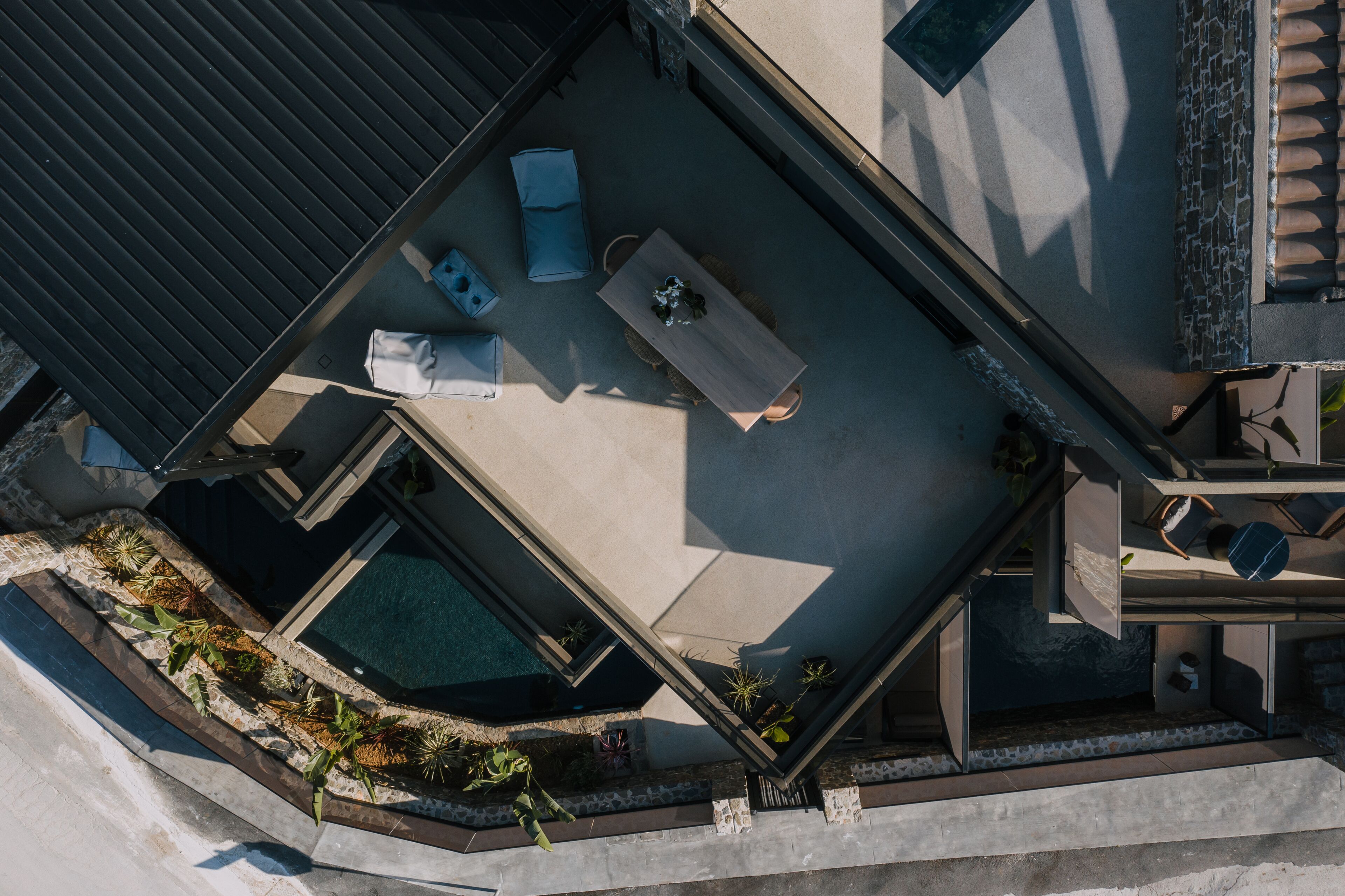 Vista aérea de um pátio moderno ao ar livre, com piscina, área de estar e plantas em vasos.
