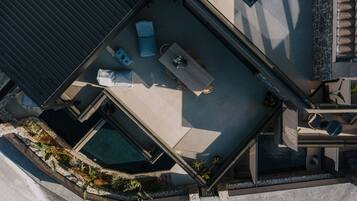 Vista aérea de um pátio moderno ao ar livre, com piscina, área de estar e plantas em vasos.
