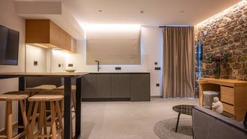 Cozinha moderna com ilha central, banquetas e parede decorada com pedra.