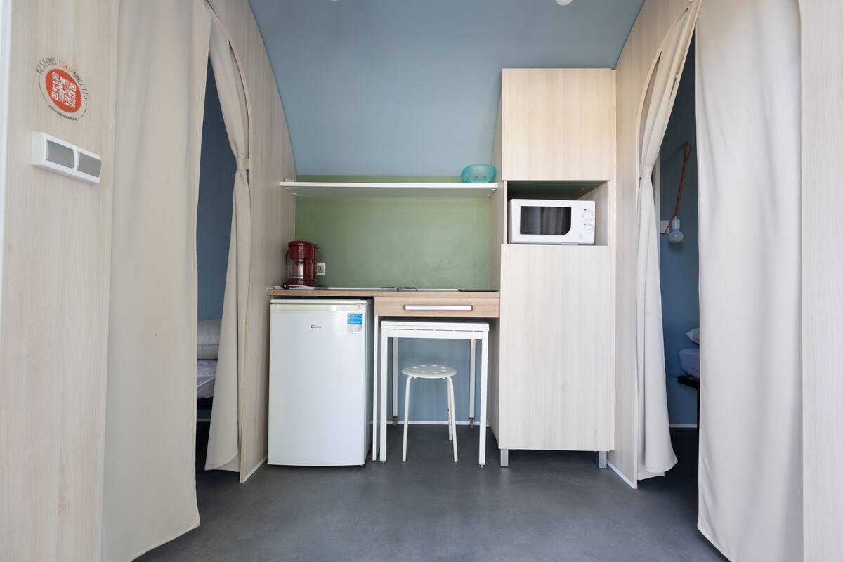 Uma cozinha compacta equipada com geladeira, micro-ondas e uma mesa pequena.