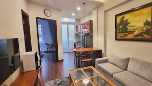 Uma sala de estar com sofá, mesa de centro, televisão e um quadro na parede.