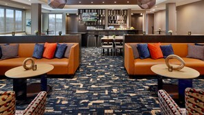 Um hall de hotel moderno com dois sofás, um bar e um espaço para refeições.