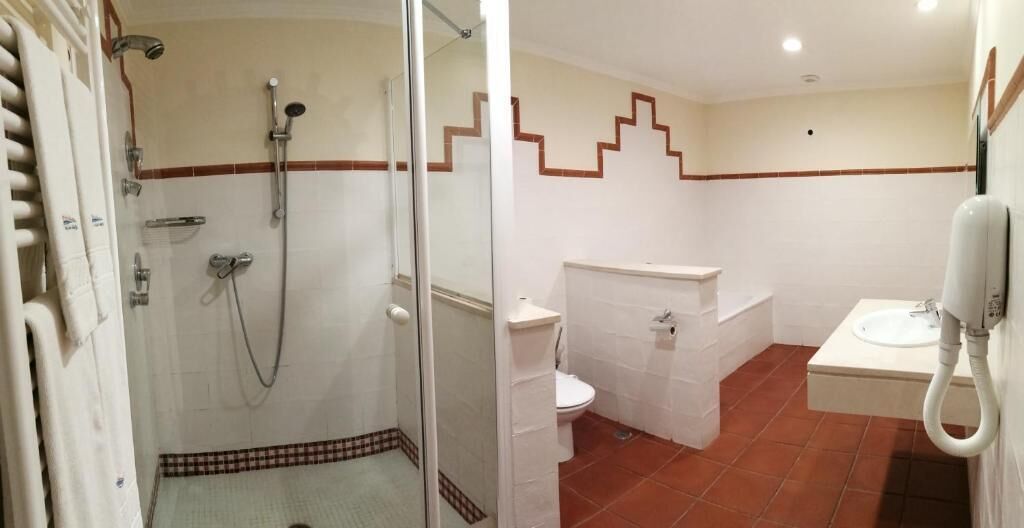 Casa de banho com chuveiro, sanita e lavatório.