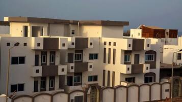 Um edifício residencial com vários andares, design arquitetônico moderno, com varandas e portão fechado.